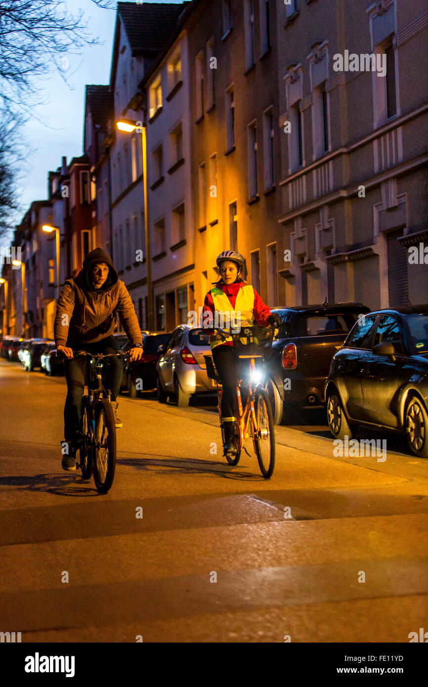 Cyclist driving, at dusk, in a city street, with and without lights and ...