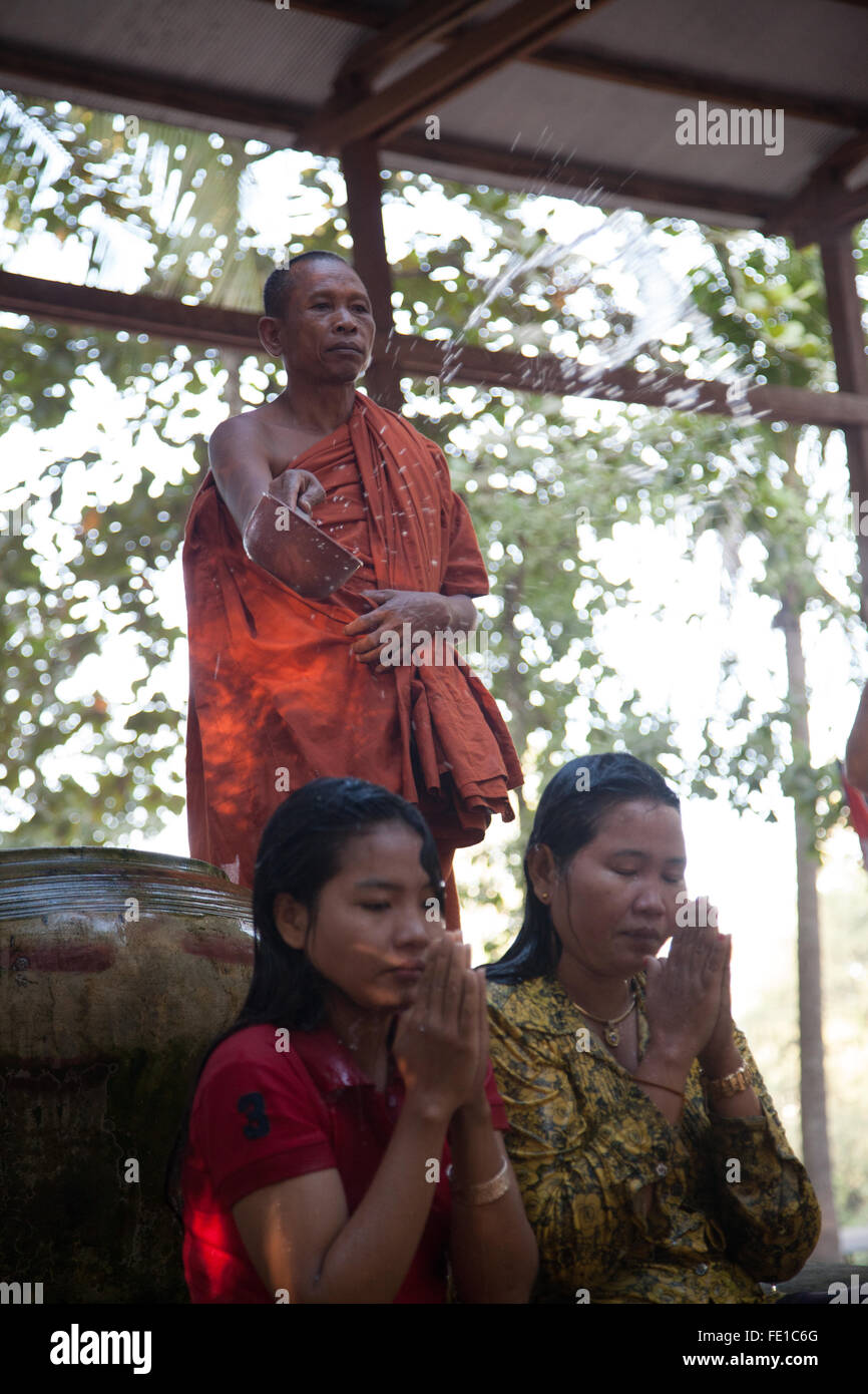 A Buddhist monk is blessing two travelers, a water ceremony,from the ...
