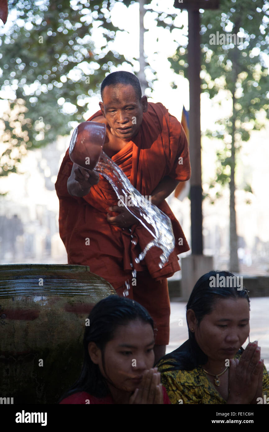 A Buddhist monk is blessing two travelers, a water ceremony,from the ...