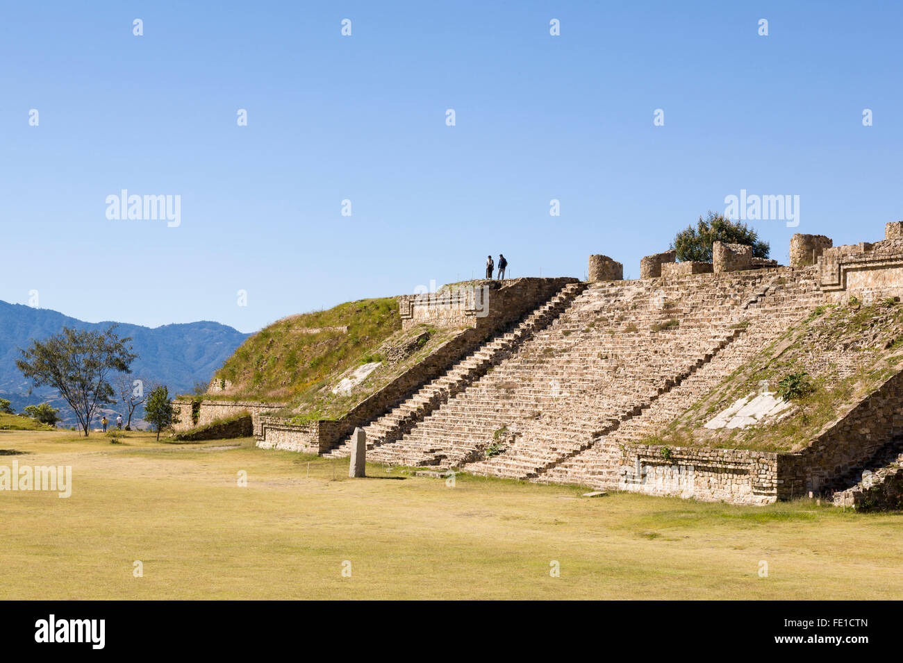 Tourists couple visiting ruins of a stone pyramid at Monte Alban, a ...