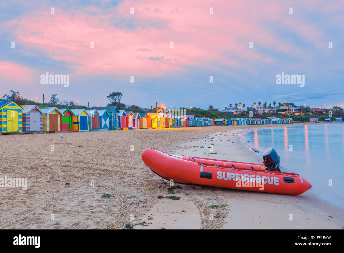 Red lifeguard rescue boat on a beach with colorful bathing huts ...
