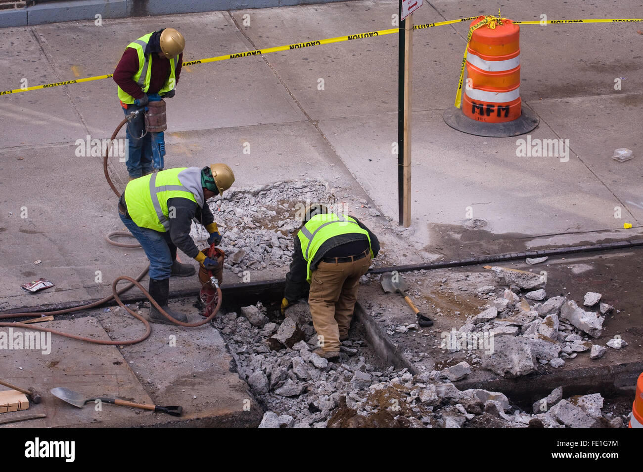 2 construction workers with jackhammers break up concrete on a city ...