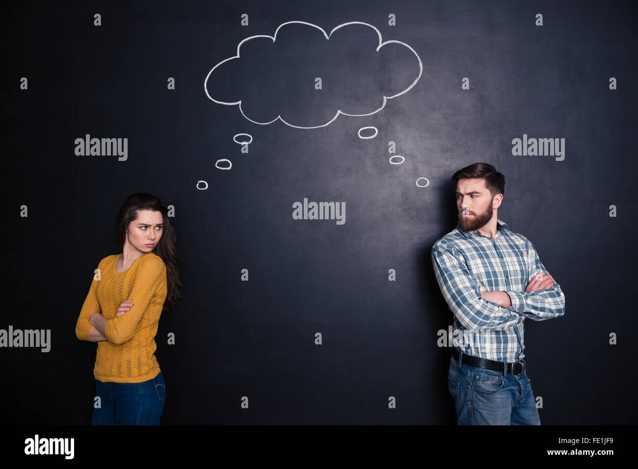 Frowning angry young couple standing with hands folded and thinking ...