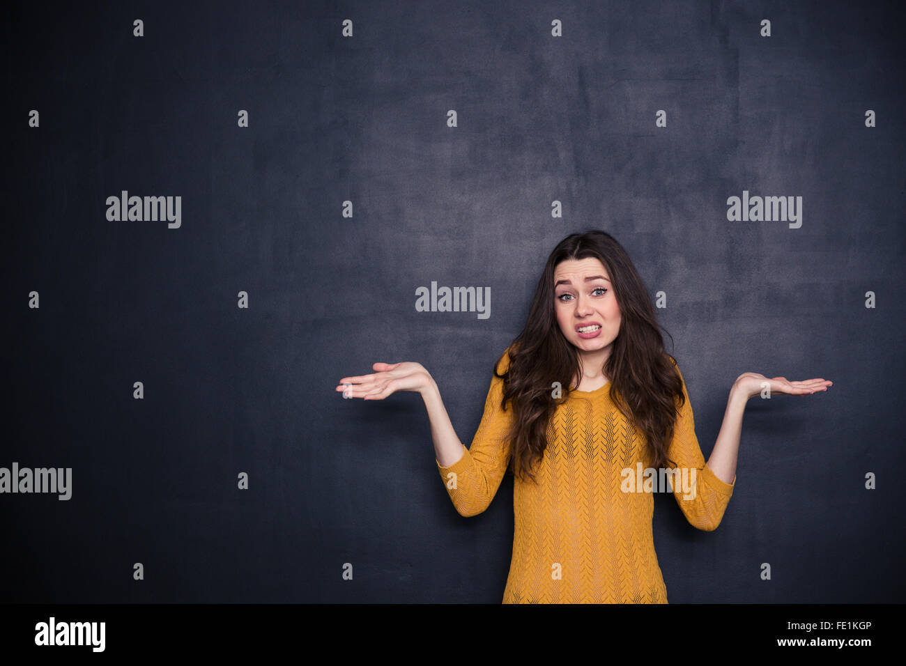 Young woman shrugging shoulders over black background Stock Photo - Alamy