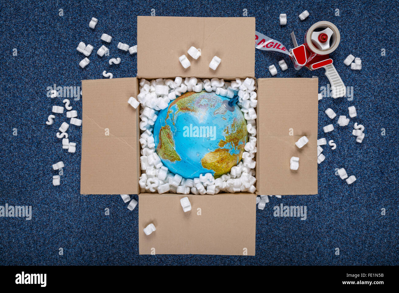 A world globe in a box surrounded by packing chips with Fragile tape ...