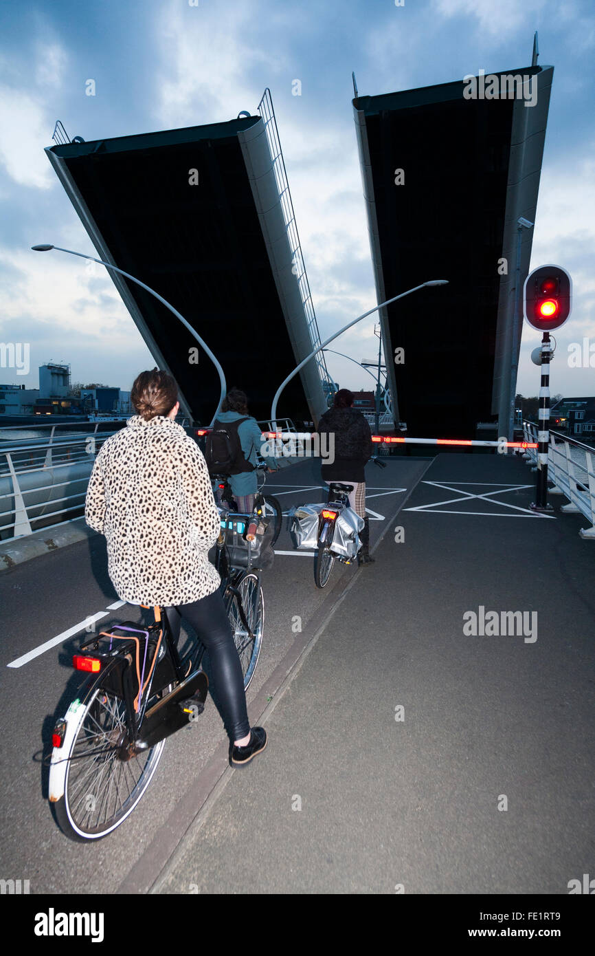 Cyclists wait as the Julianabrug Juliana Bridge opens to let a ship ...