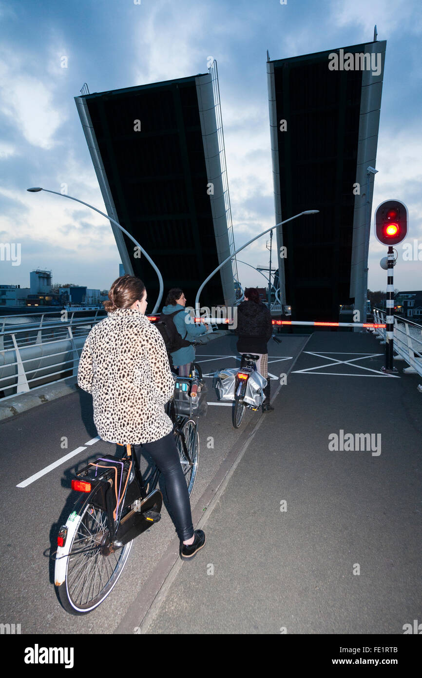 Cyclists wait as the Julianabrug Juliana Bridge opens to let a ship ...