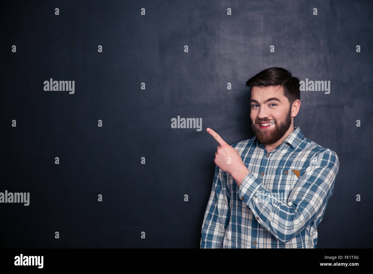 Happy man pointing finger away over black background Stock Photo - Alamy