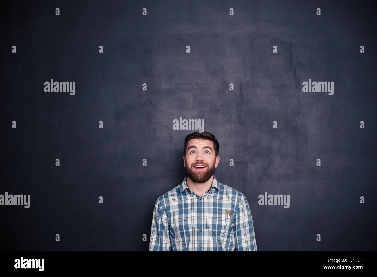Smiling casual man looking up at copyspace over black background Stock ...