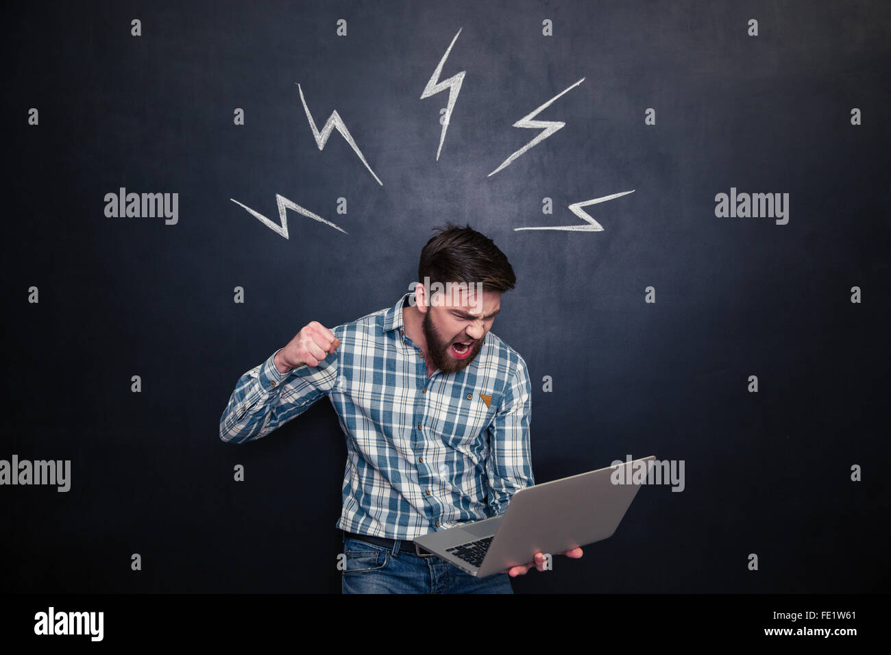 Aggressive young man yelling and going to break laptop with fist over ...
