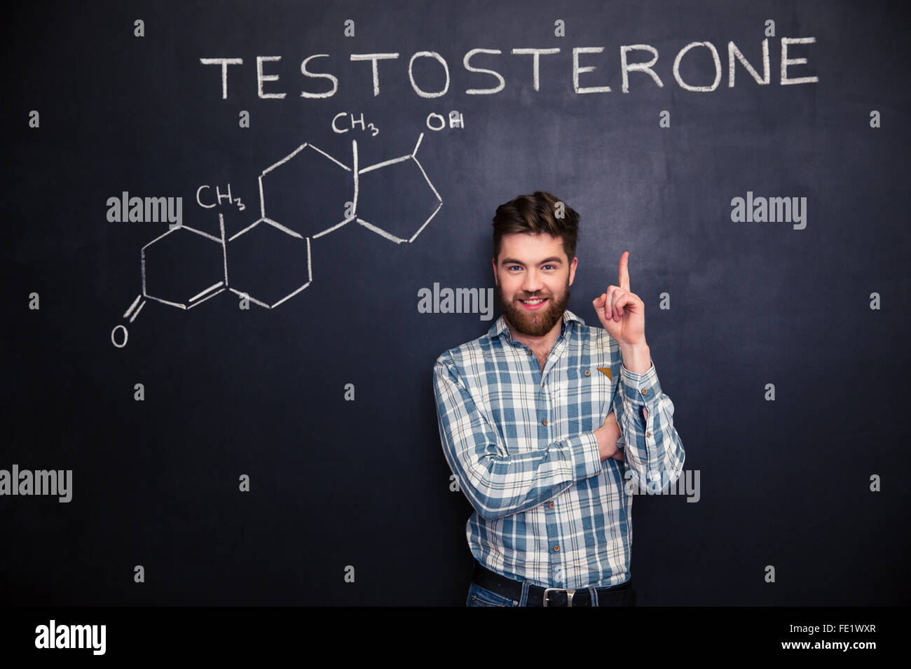 Confident smiling young man pointing up on chemical structure of ...