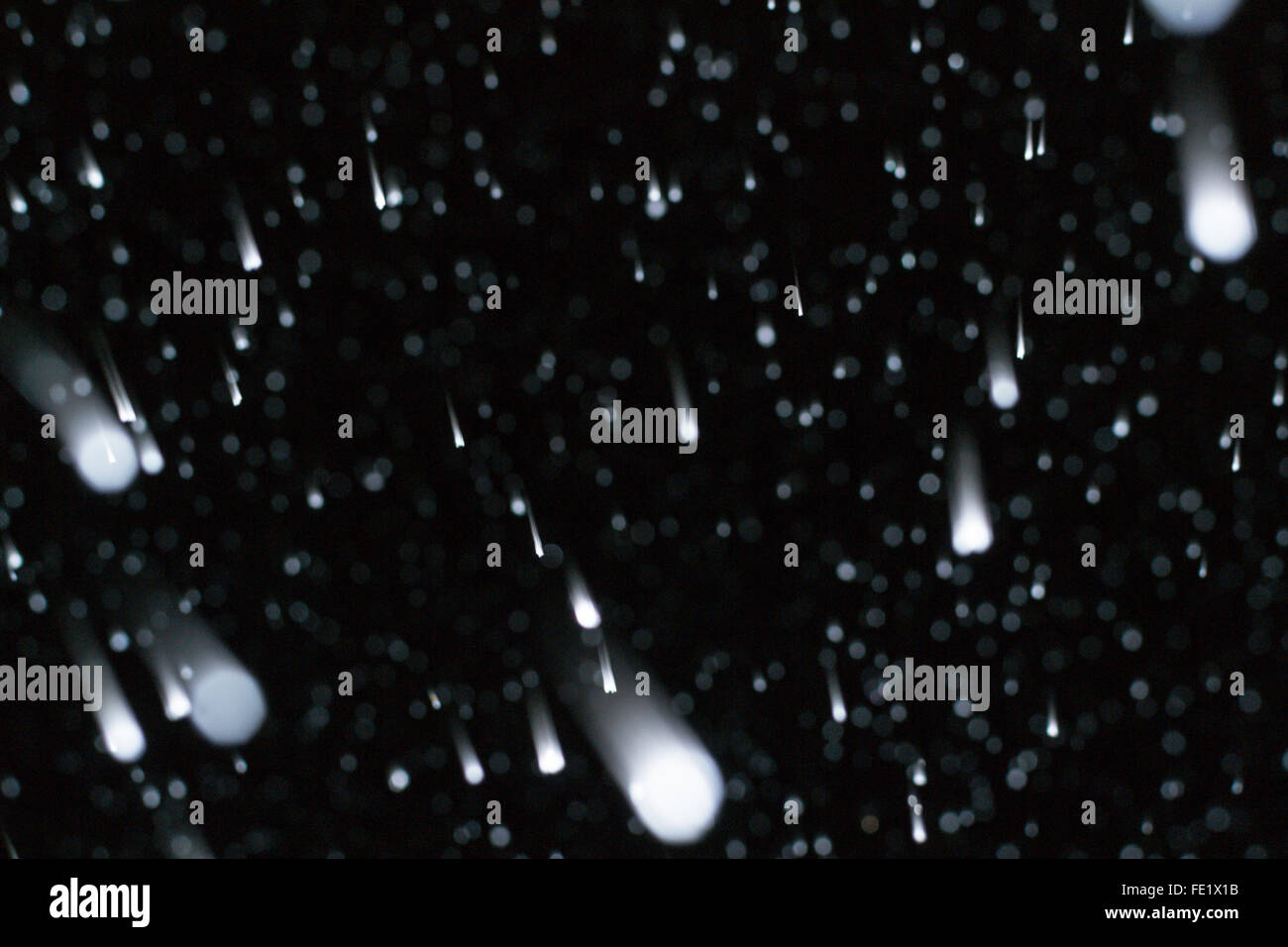 Flakes of natural snow falling at night set against a black background ...