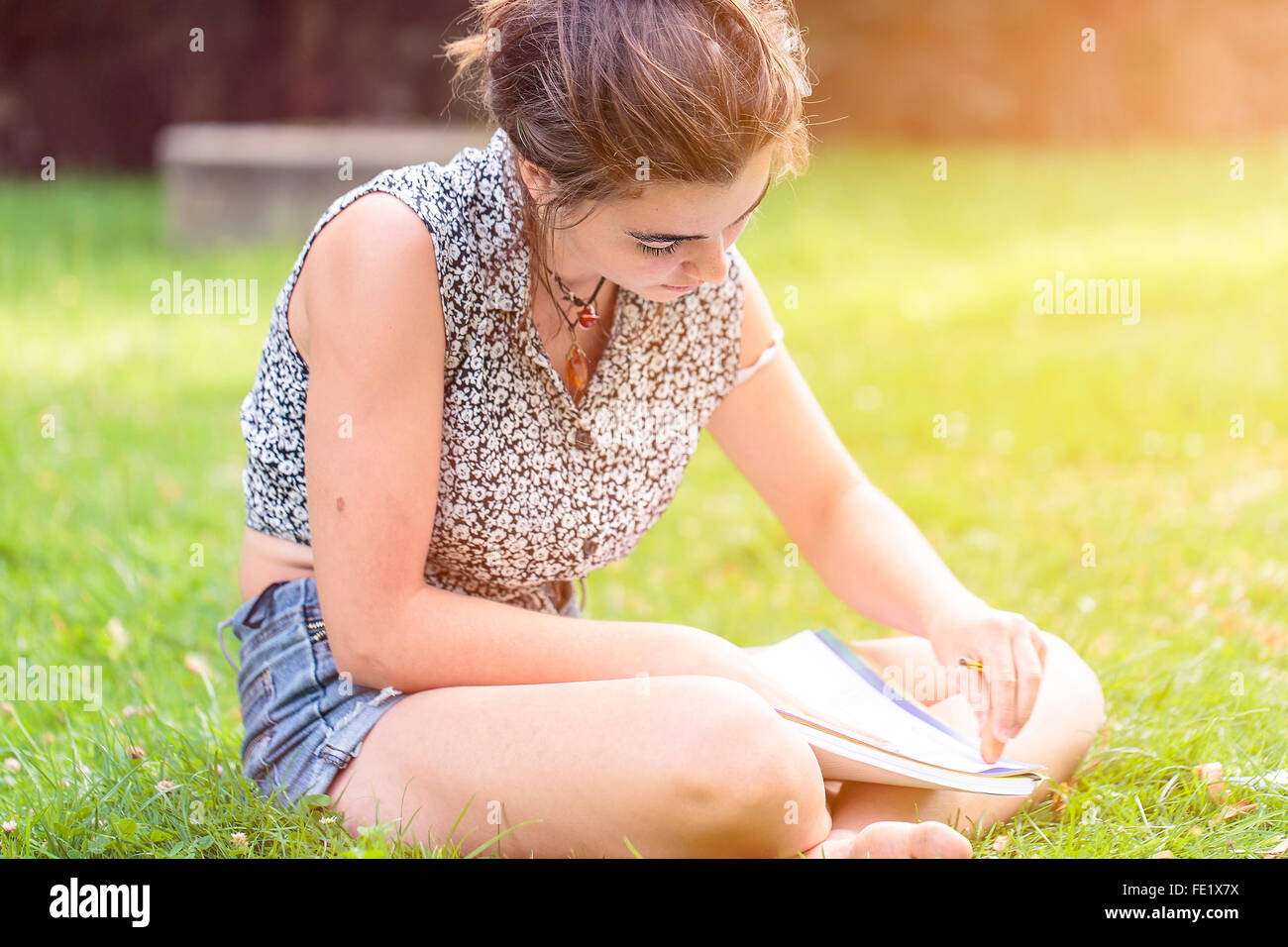 teenage girl making here homework sitting in a garden Stock Photo - Alamy