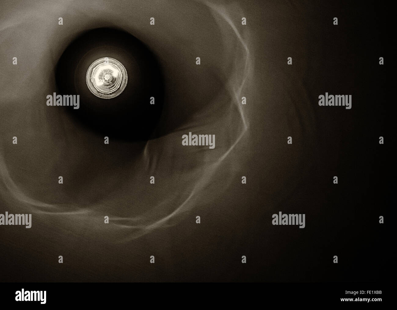 Sepia Toned light bulb hangs from a gloomy ceiling creating a grunge ...