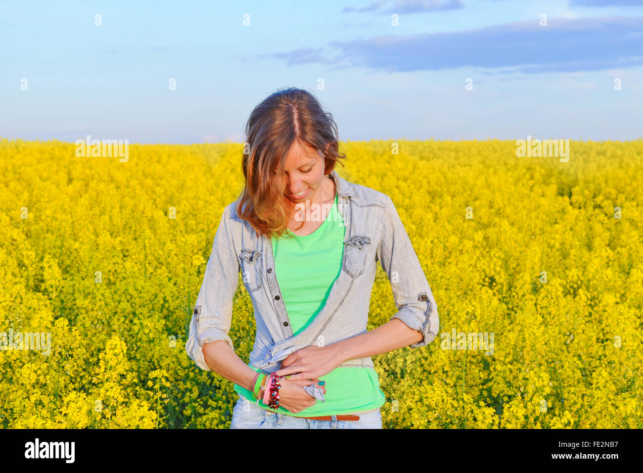 Brunette girl buttoning her shirt in a field of yellow flowers Stock ...