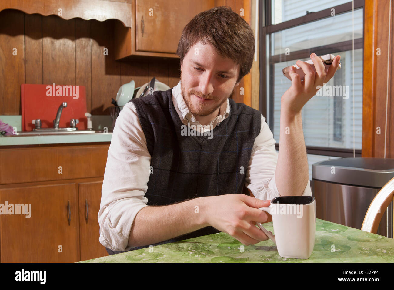 Blind man in his kitchen listening to assistive technology on his cell ...