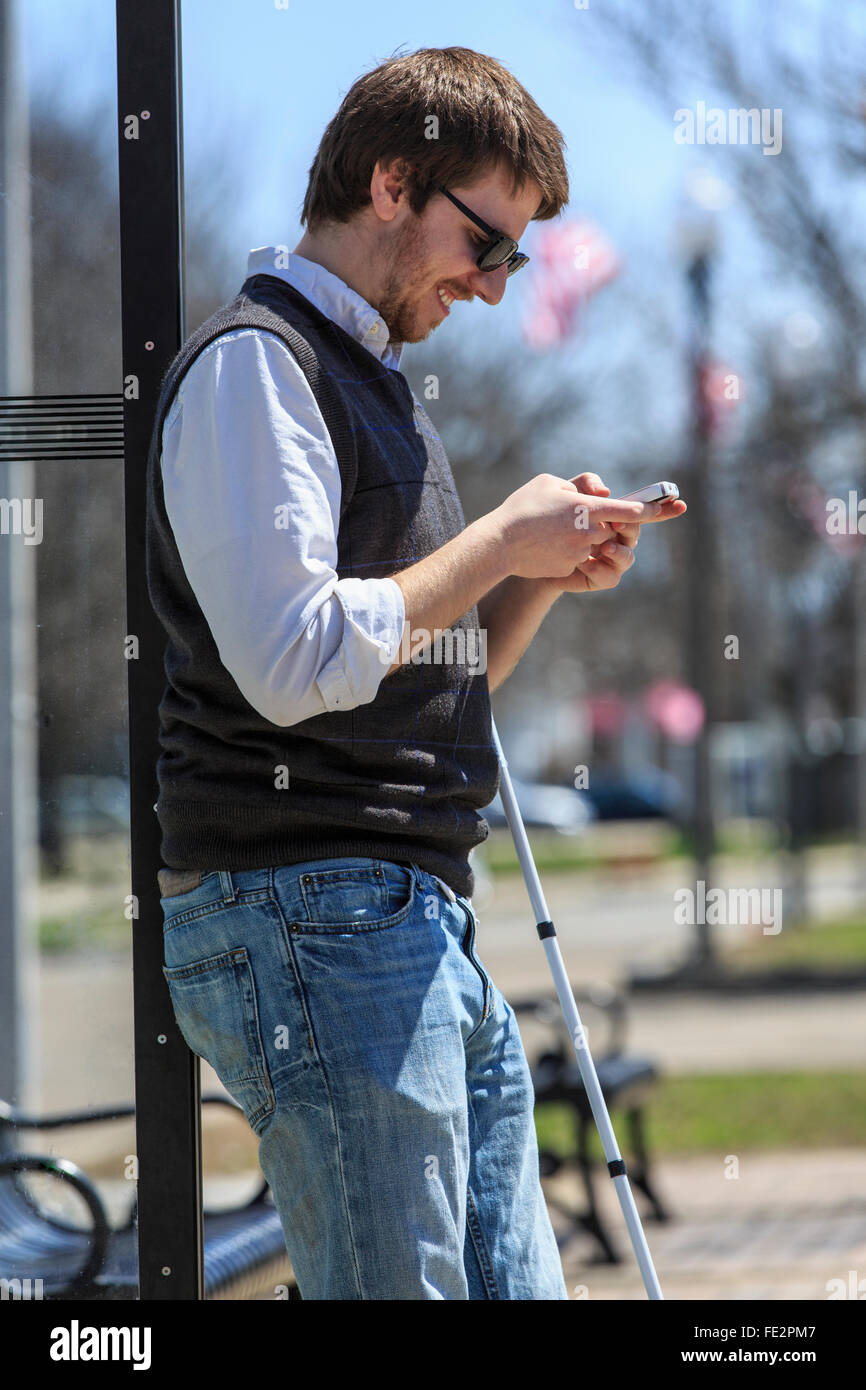 Young blind man at a bus stop using assistive technology Stock Photo ...