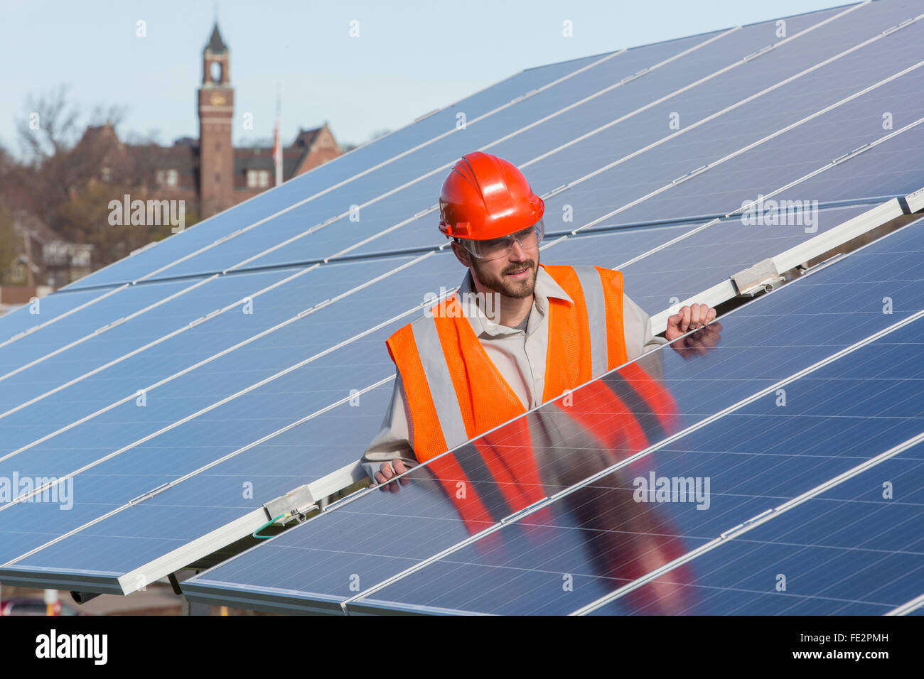 Power engineer at solar photovoltaic array examining surface of panels ...