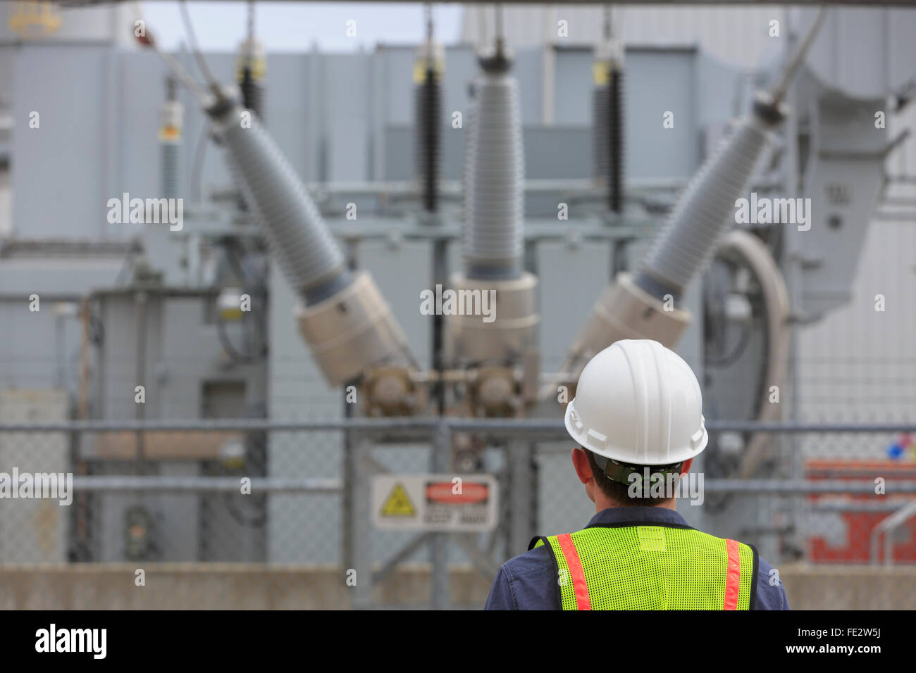 Industrial engineer examining high voltage transformer at a power plant ...