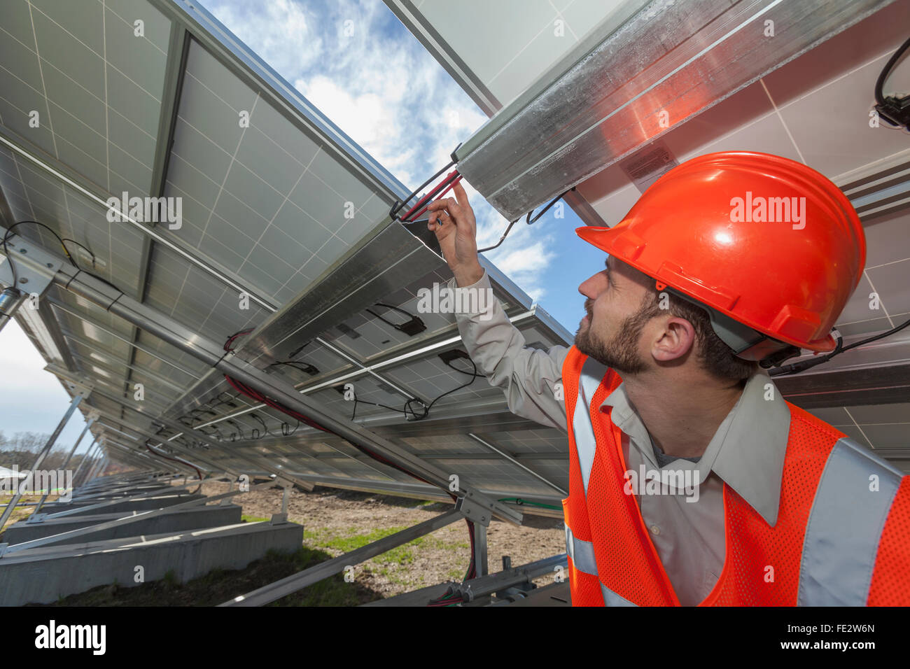 Power engineer examining power cabling of solar photovoltaic array ...