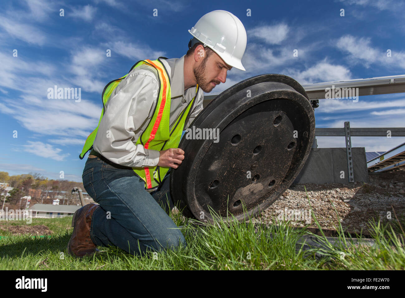 Solar photovoltaic installer examining an inspection port at a power ...
