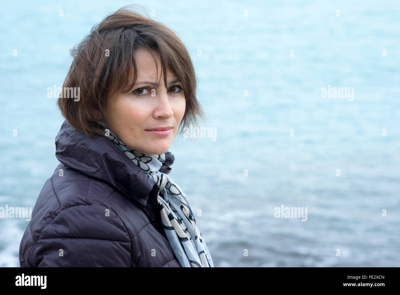 Woman standing in windy conditions in front of the sea Stock Photo - Alamy