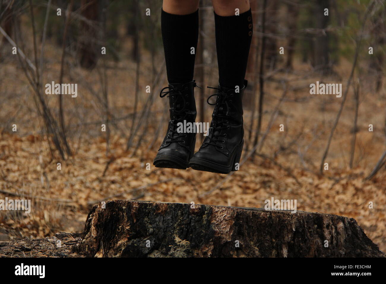 Low Section Of Woman Jumping On Tree Stump Stock Photo - Alamy