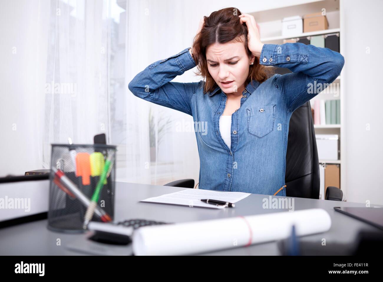 Stressed businesswoman under pressure sitting holding her head with her ...
