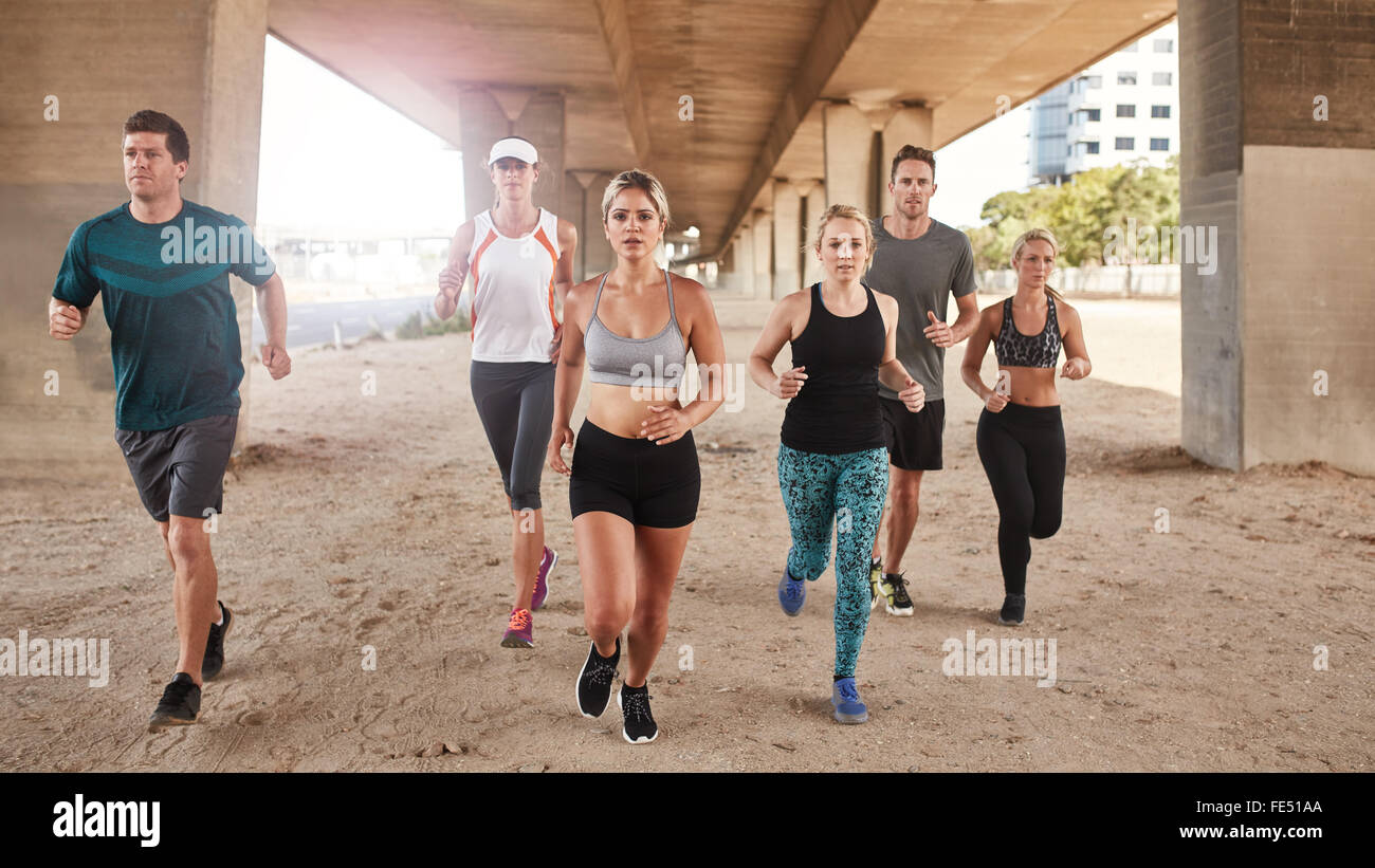 Healthy young people running together under a bridge. Group of young ...