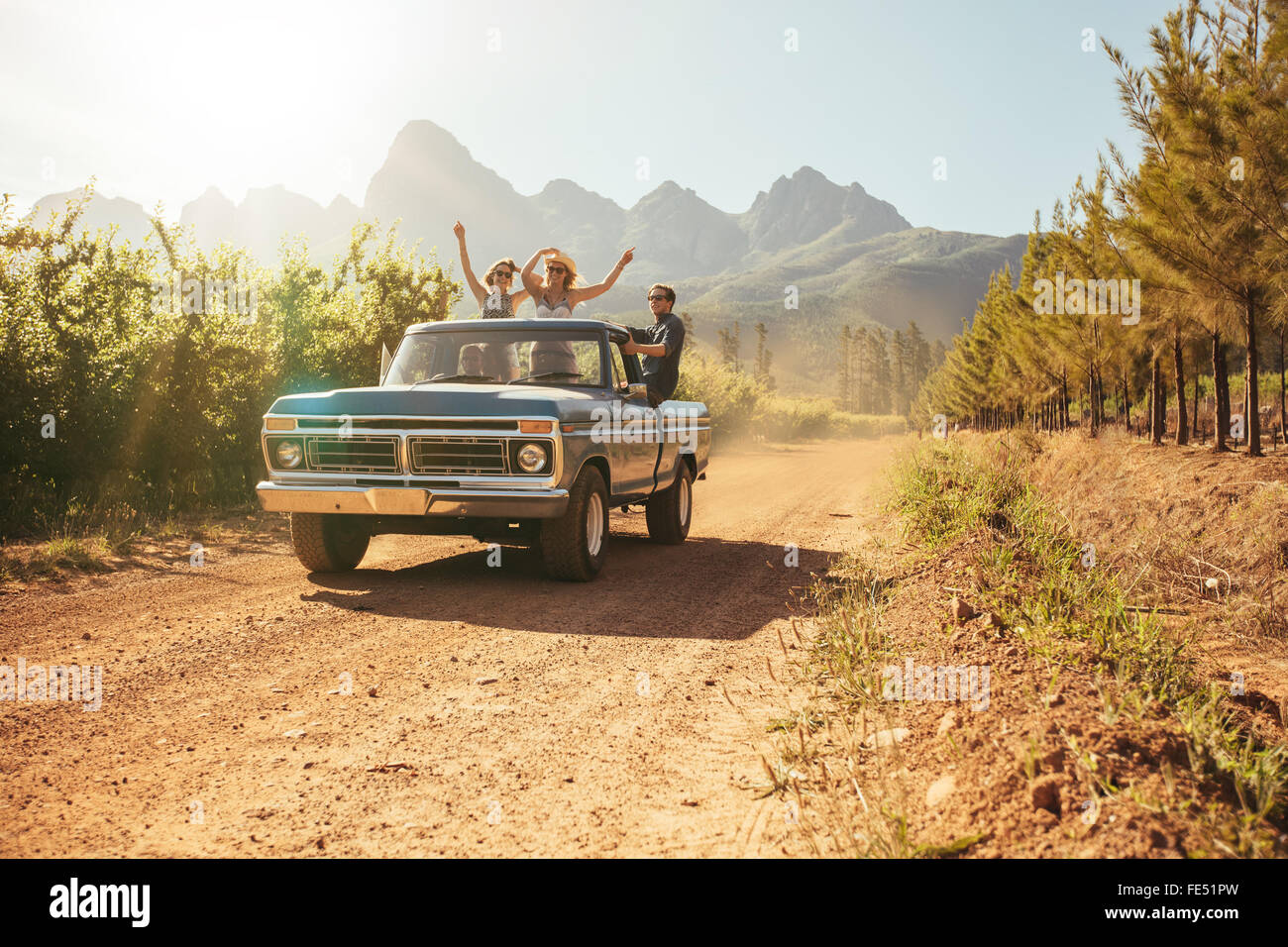 Friends having fun in the open back of a vintage truck on a summer day ...