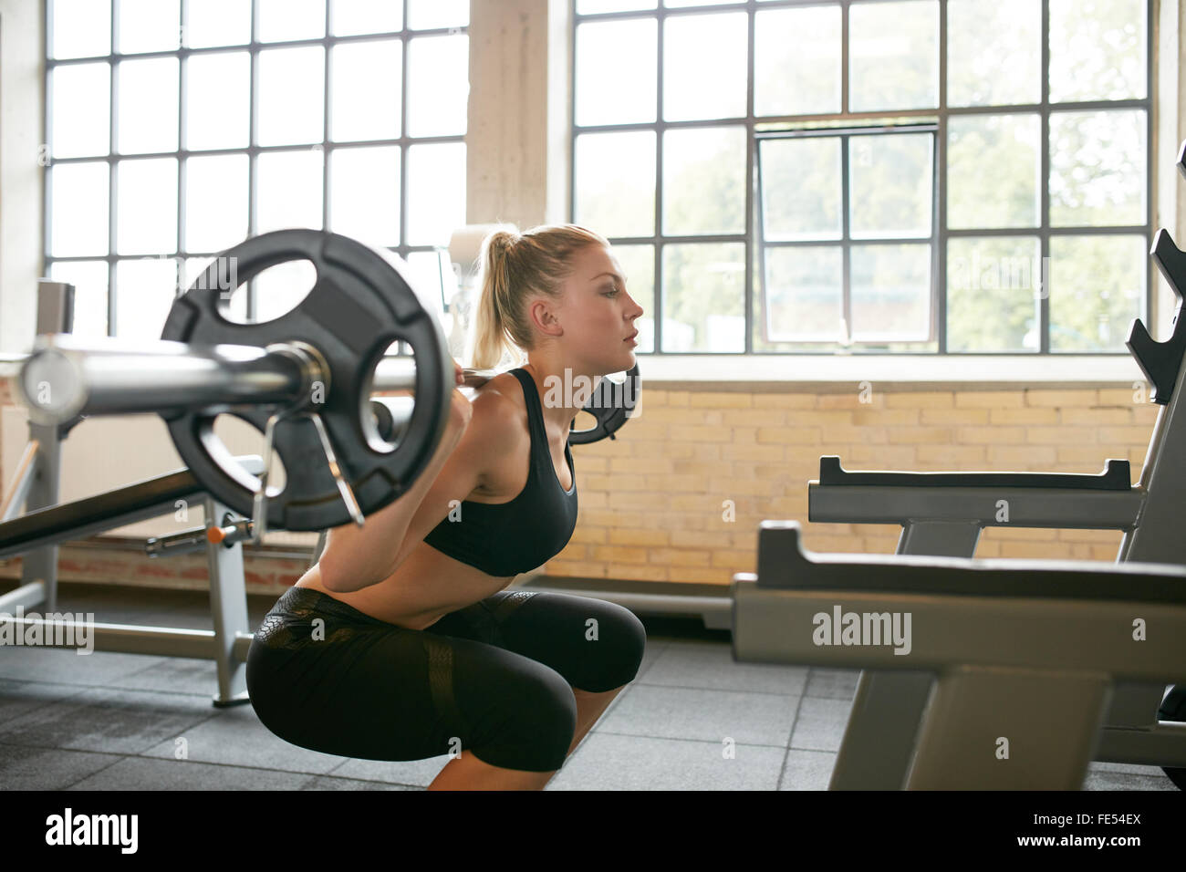 Female working out in a gym doing squats. Young woman working out using ...