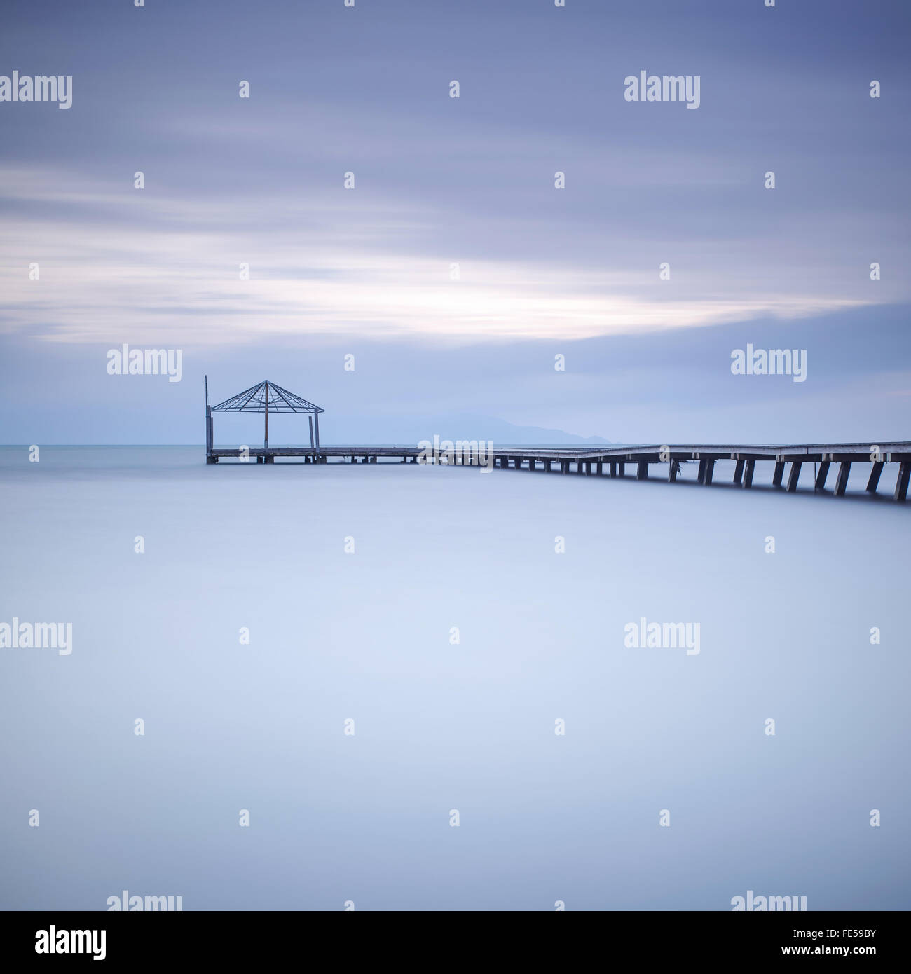 Wooden pier or jetty silhouette in a blue ocean on sunset. Long ...