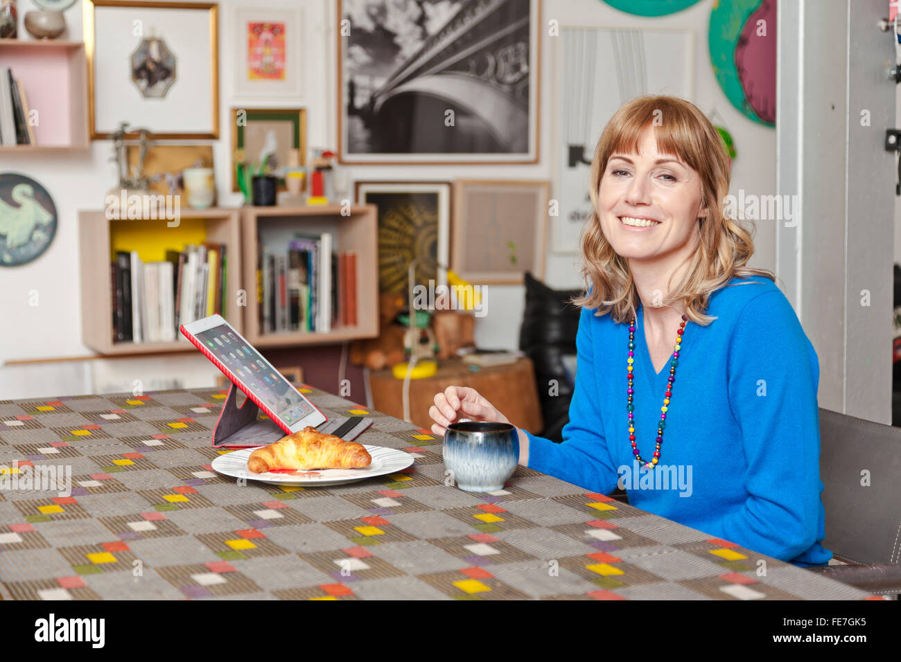 Woman sitting at a living room table Stock Photo - Alamy