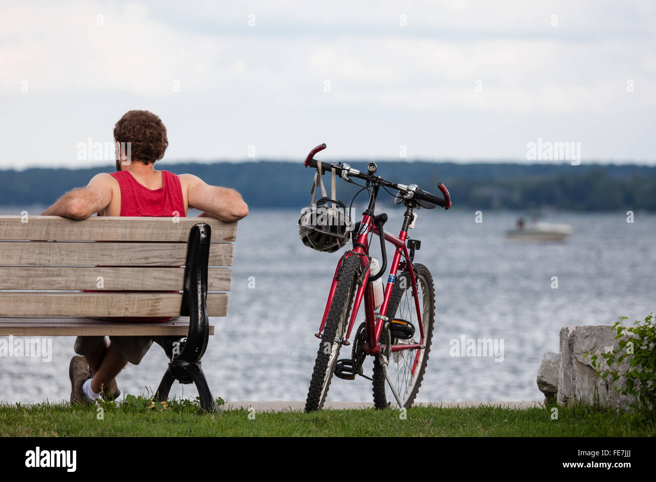 Cyclist resting on a park bench at the waterfront Stock Photo - Alamy