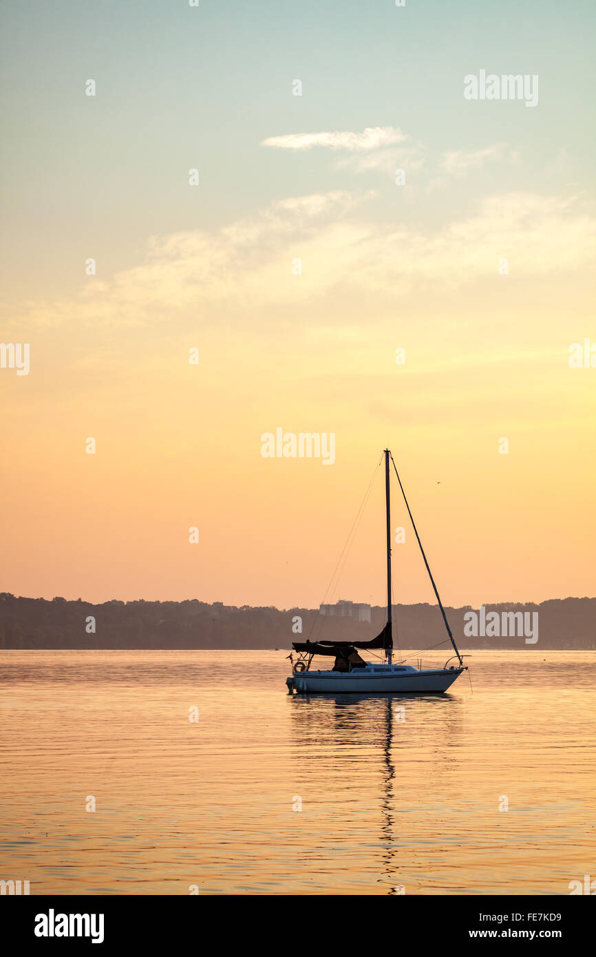 Waterfront scene of a Sailboat at sunrise, with a reflection in the ...