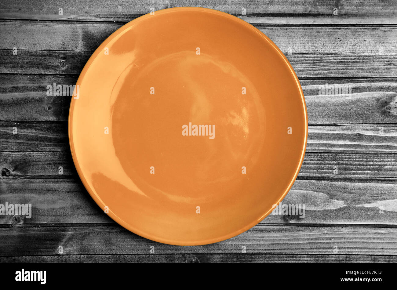 Empty orange plate on gray wooden table Stock Photo - Alamy