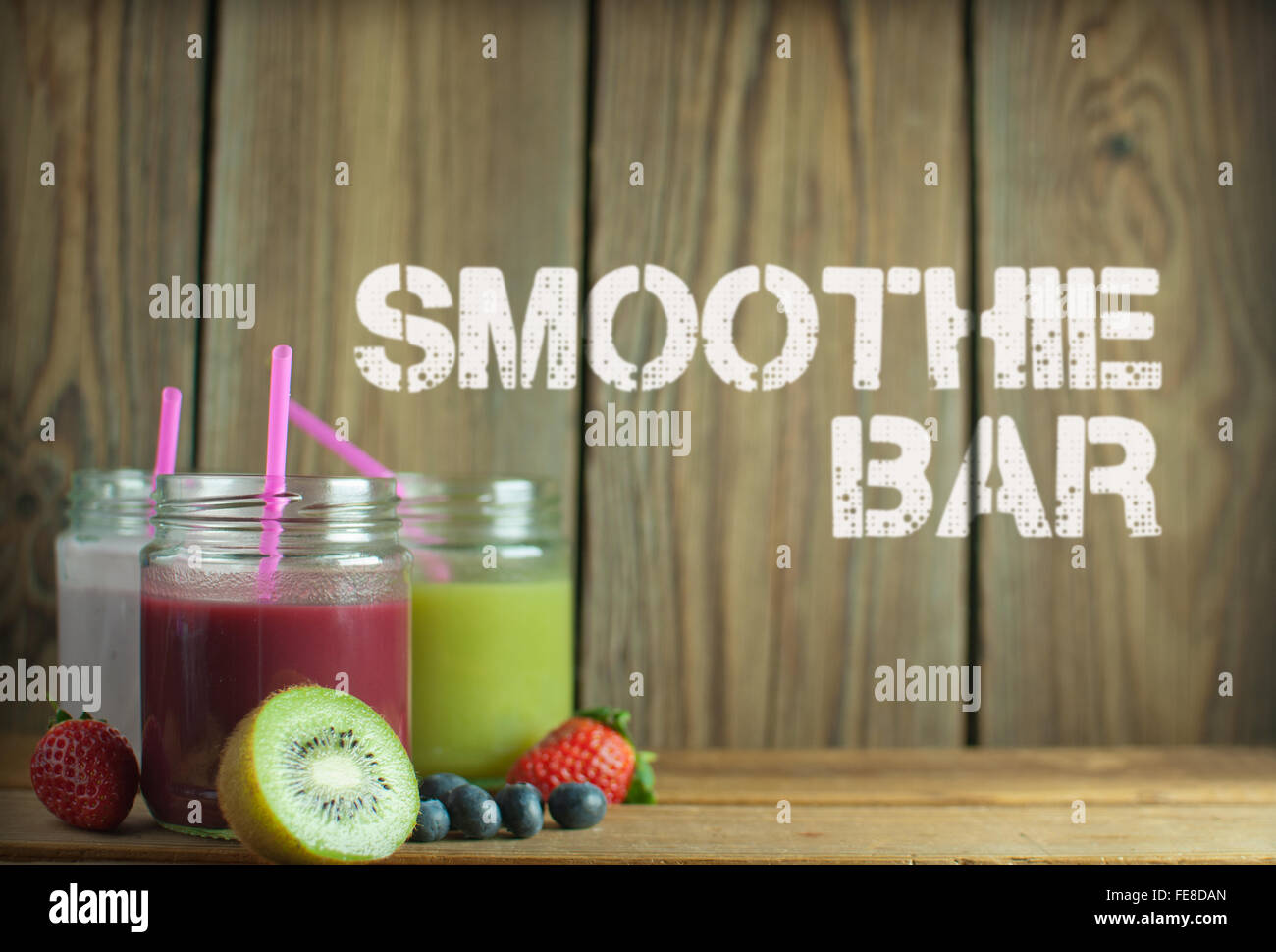 Flavored smoothies including berry and kiwi with wooden background ...