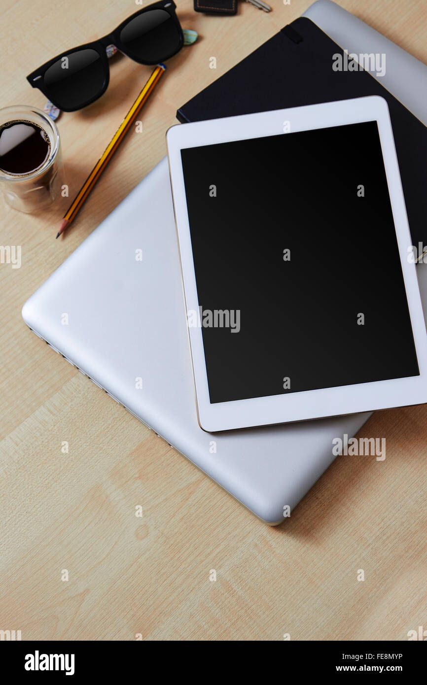 Tablet pc with blank screen and other devices on a wooden desk, flat ...
