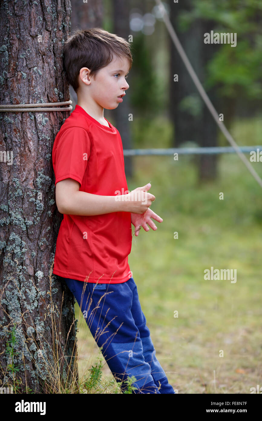 Sad little boy standing under the tree Stock Photo - Alamy