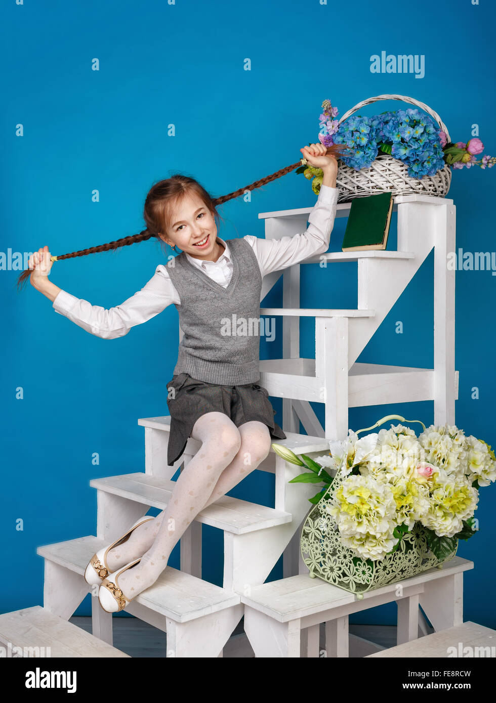 Cute teen girl in school uniform indulges. Girl sitting on the steps ...