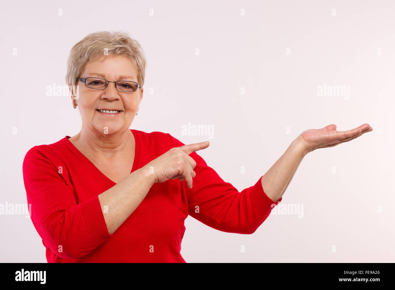 Happy smiling elderly woman showing empty hand, copy space for text Stock Photo - Alamy