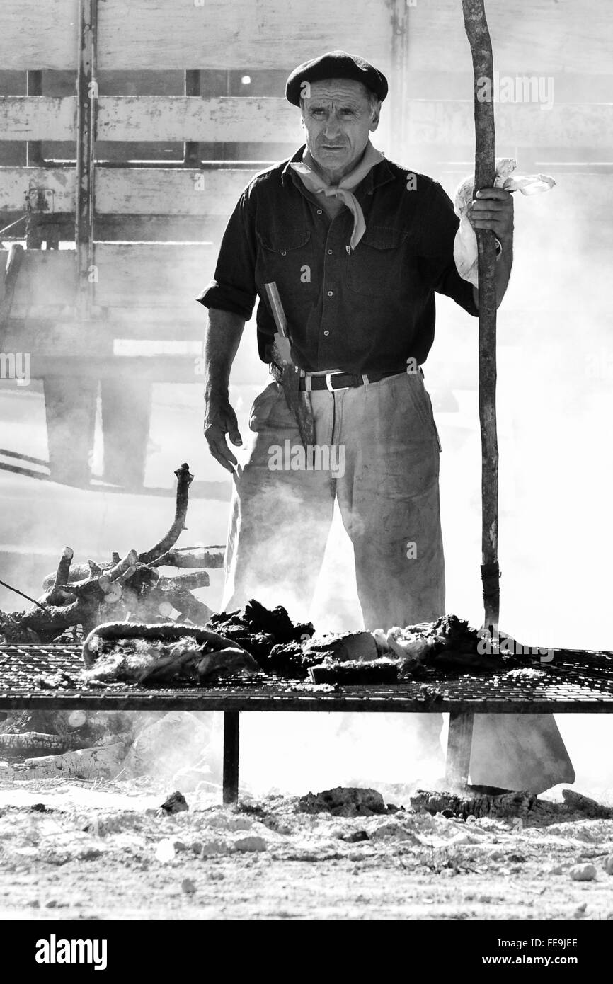 Real life candid shot of argentinian farmer checking a barbecue ...