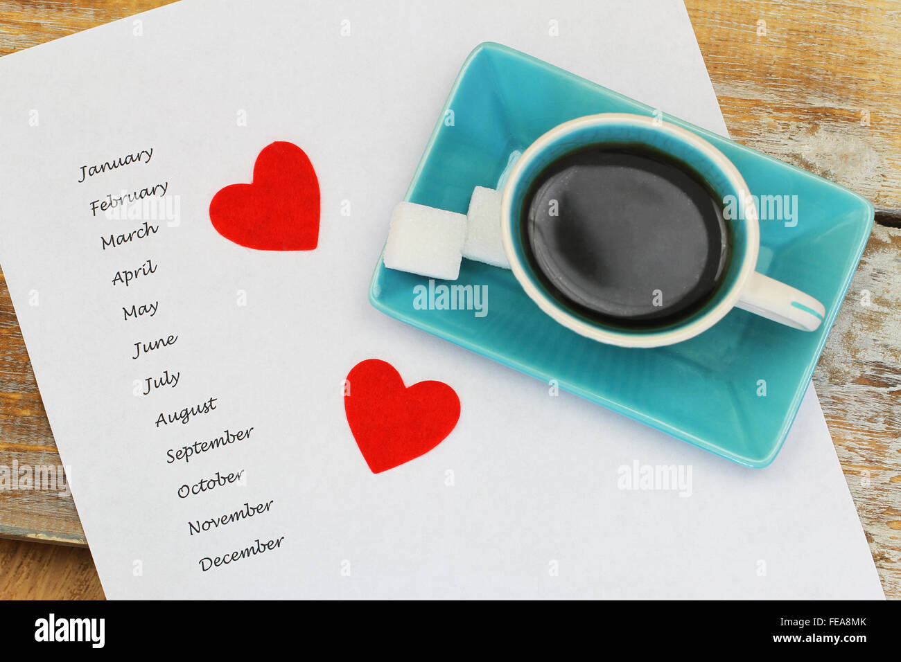 Months written on white piece of paper with cup of coffee and two red ...