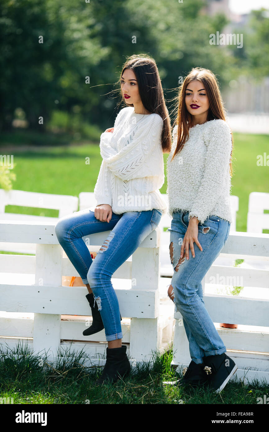 Two girls lean on a white bench in the park Stock Photo - Alamy