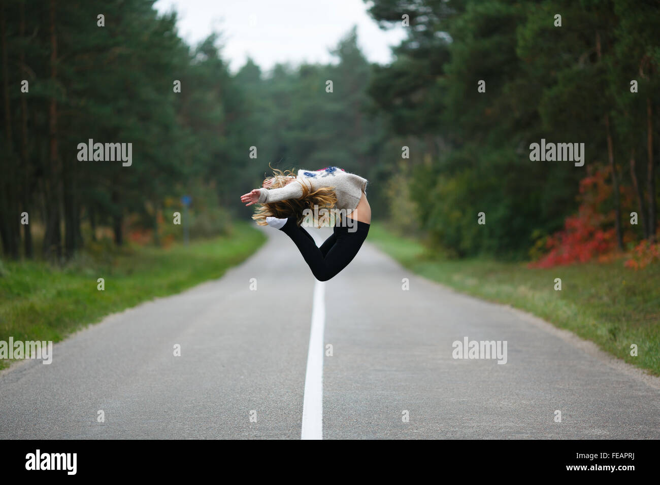 Young professional gymnast jumping on the road at autumn time Stock ...