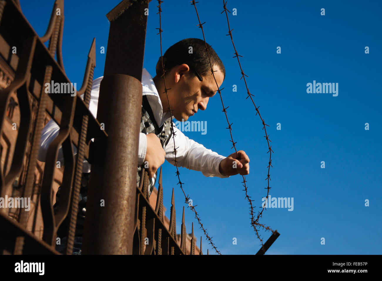 Man behind a barbed wire on the blue sky background Stock Photo - Alamy