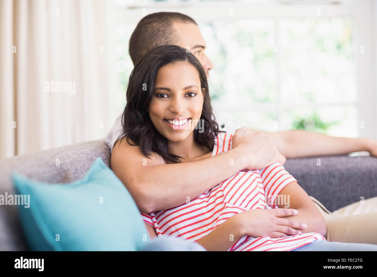 Happy couple hugging on the couch Stock Photo - Alamy