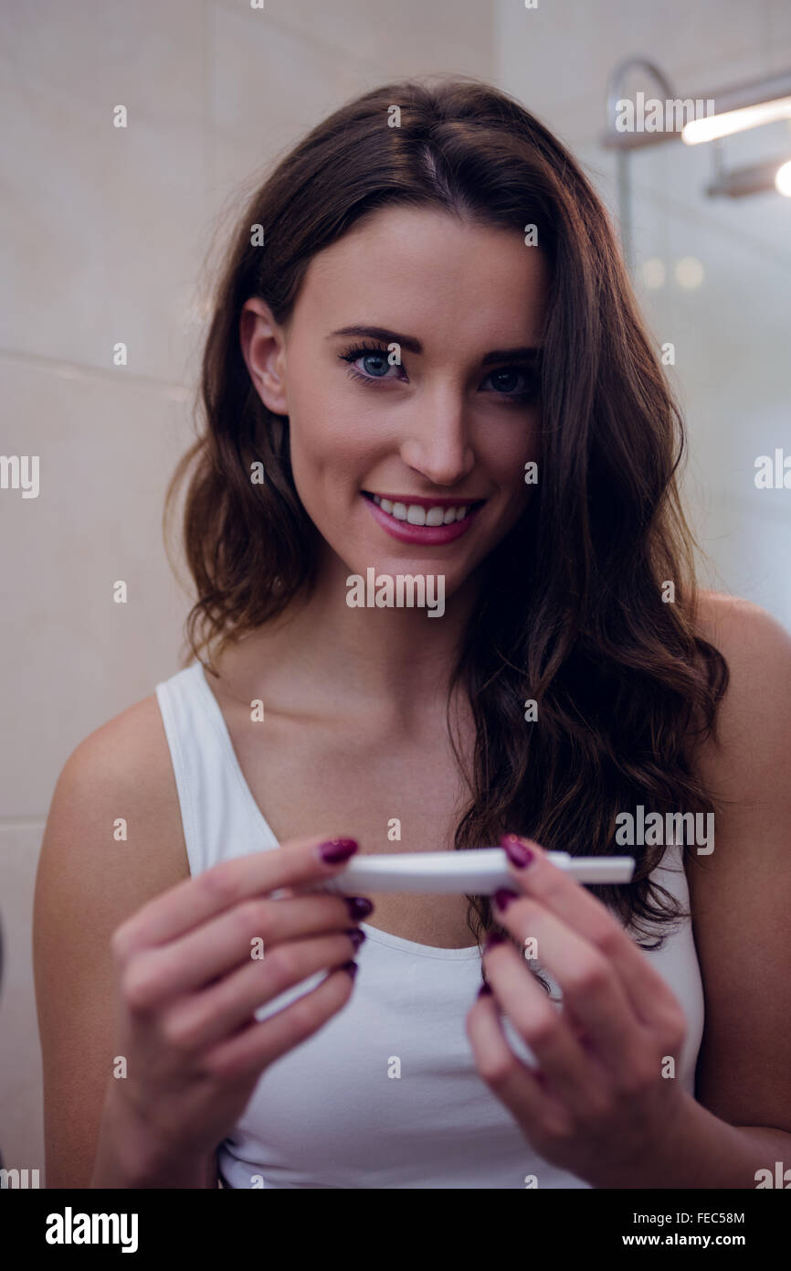Happy beautiful brunette holding a pregnancy test Stock Photo - Alamy