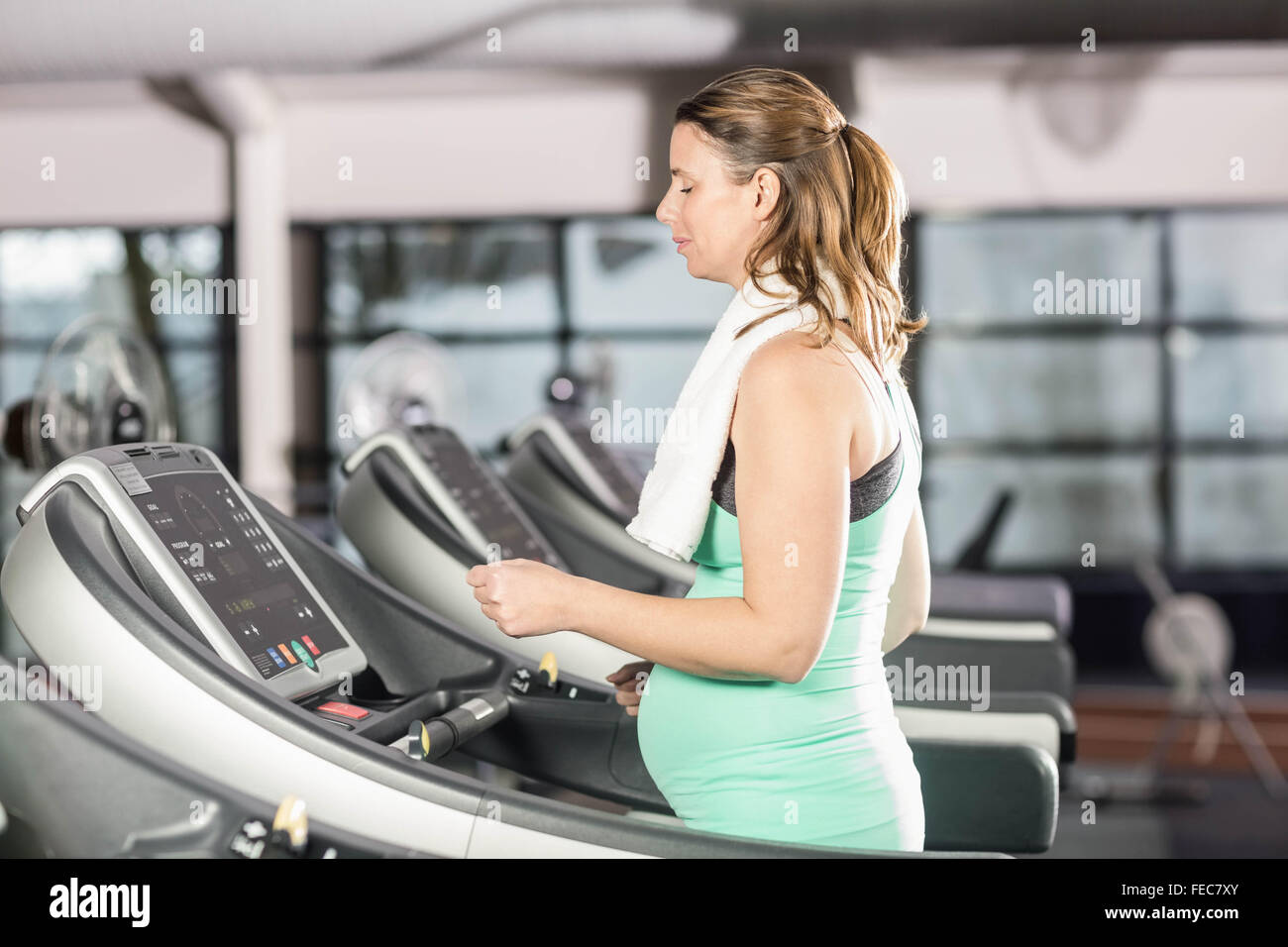 Smiling pregnant woman using treadmill Stock Photo - Alamy