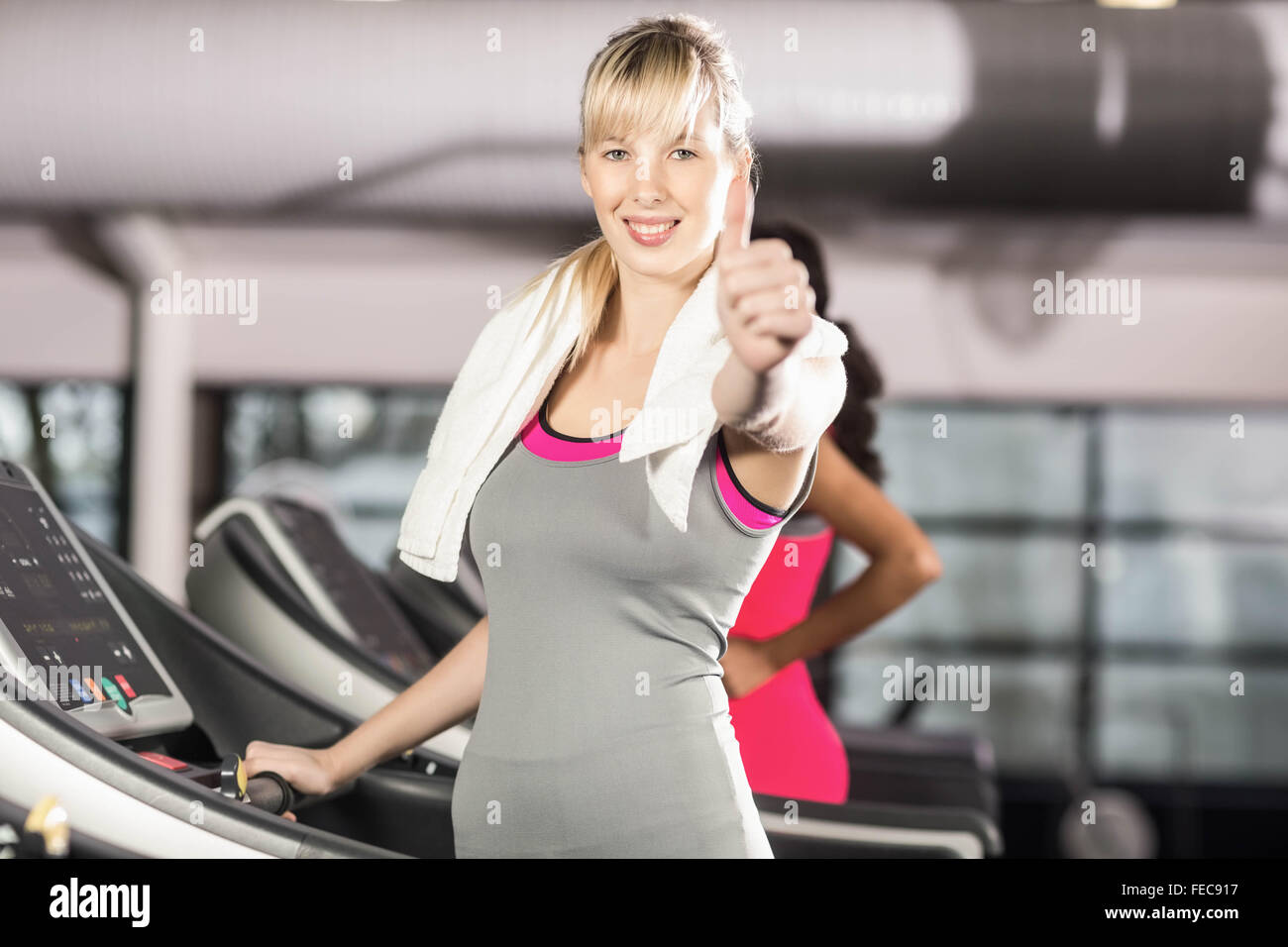 Smiling woman on treadmill showing thumb up Stock Photo - Alamy